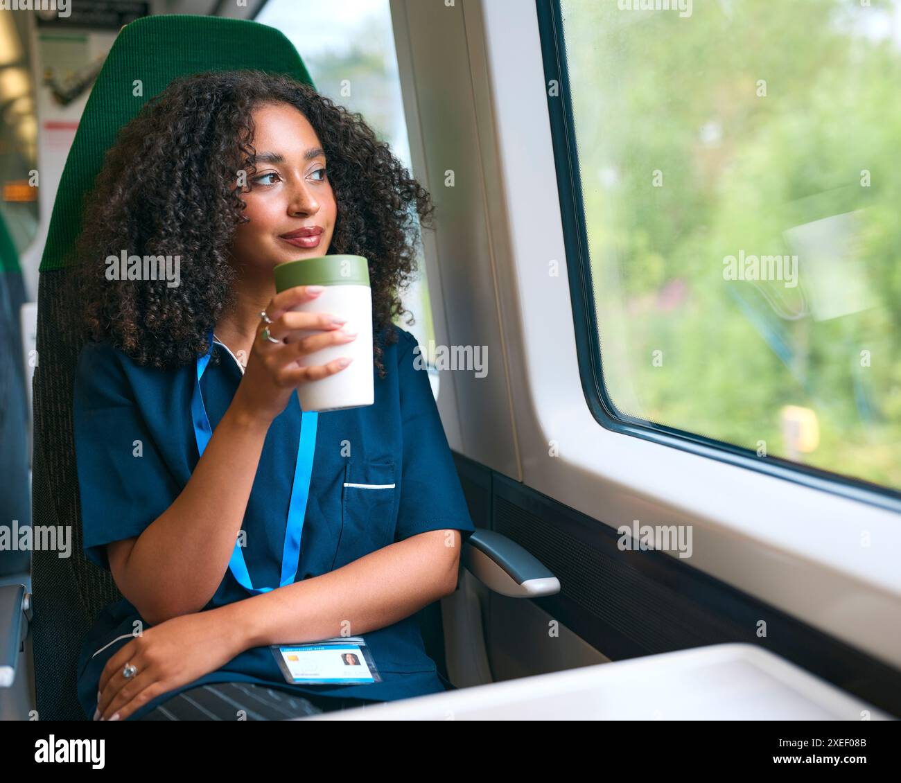Female Doctor Or Nurse Commuting On Train Holding Reusable Coffee Cup ...