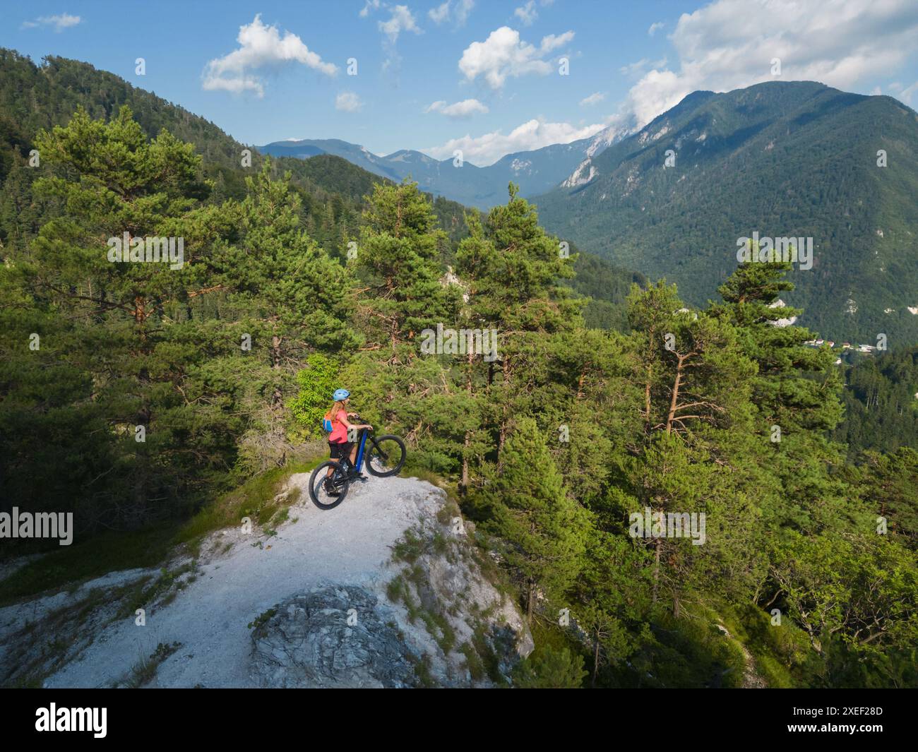 Female biker riding an electric mountain bike on a fine white stone ...
