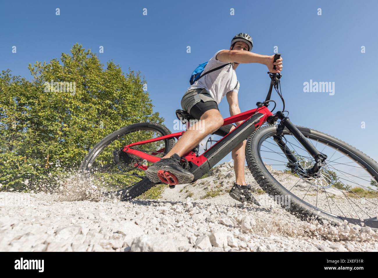 Male electric mountain bike rider going downhill and braking on a hilly ...