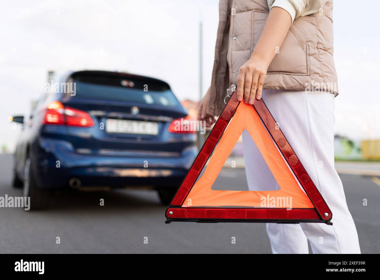 A woman driver puts a triangular road sign due to a car breakdown on ...