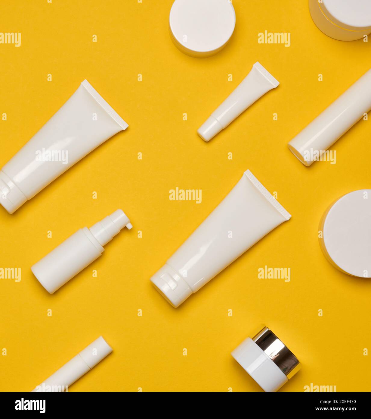 Various types of white plastic packaging, bottle, jar, tube on a yellow ...