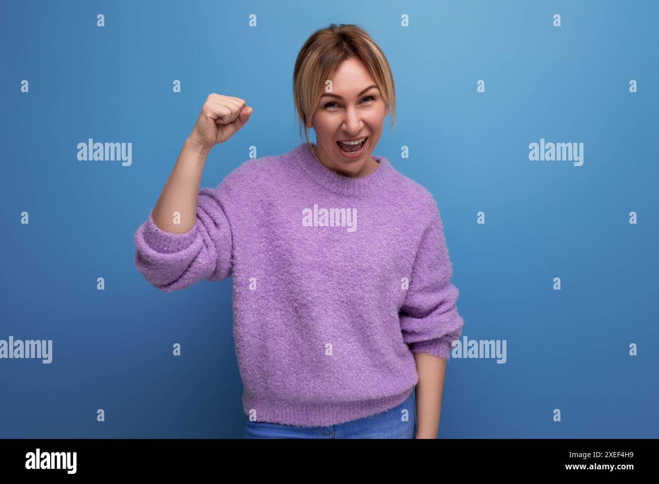 Portrait of a joyful smiling blond young woman in a casual look with a ...