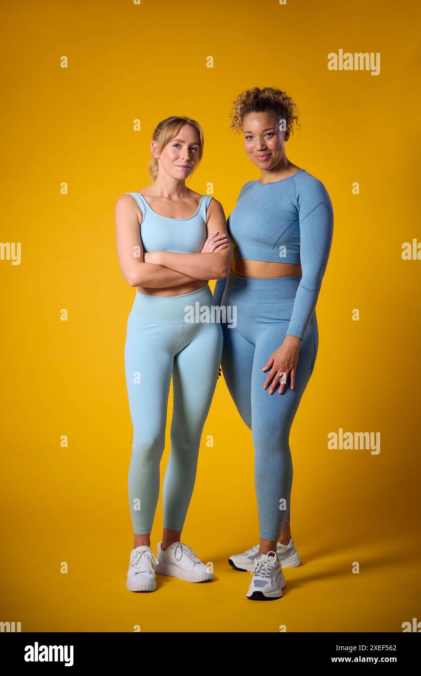 Studio Portrait Of Two Smiling Women Wearing Gym Fitness Clothing ...