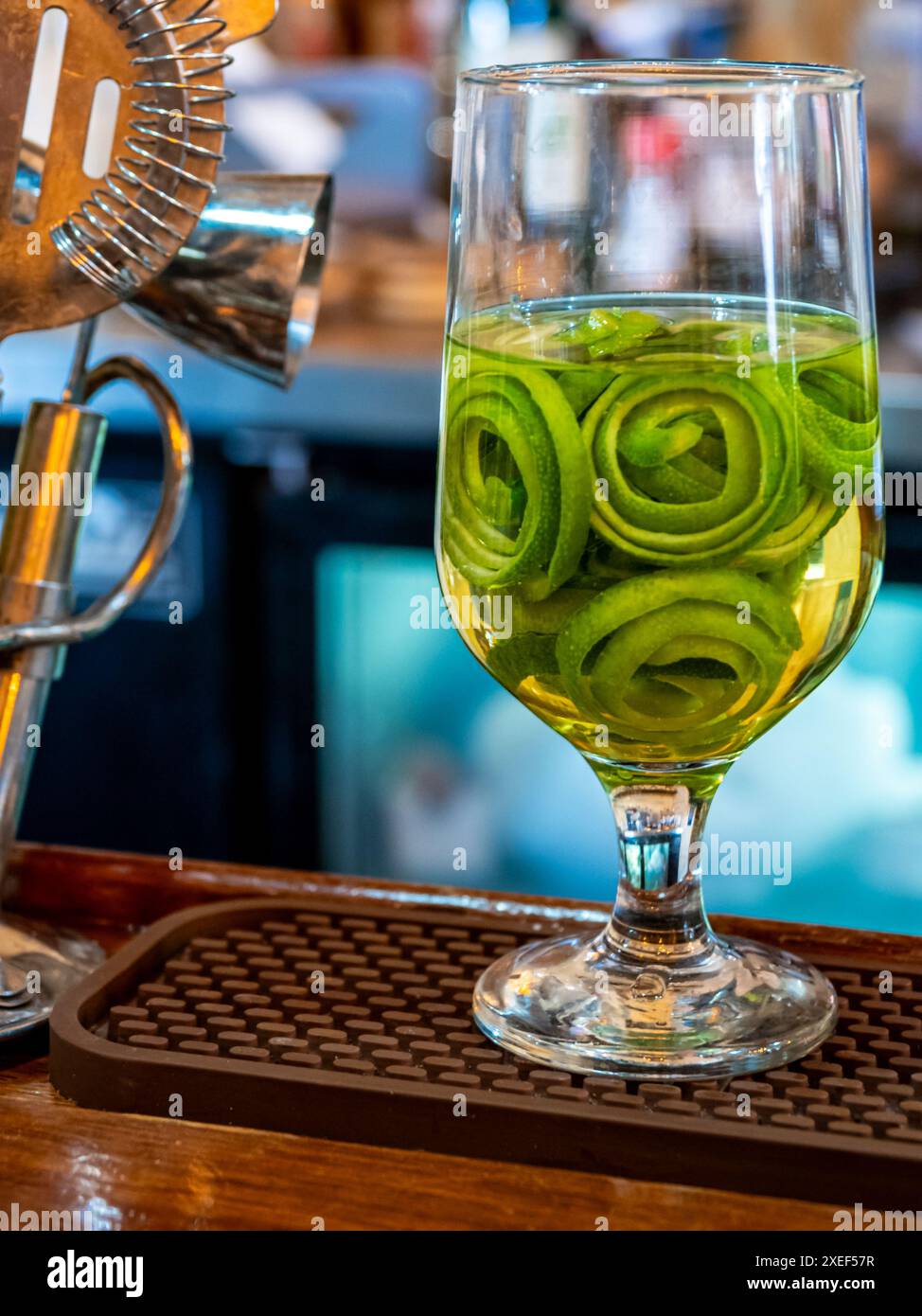 A glass with vibrant green lime peel spirals soaked in alcohol poised ...