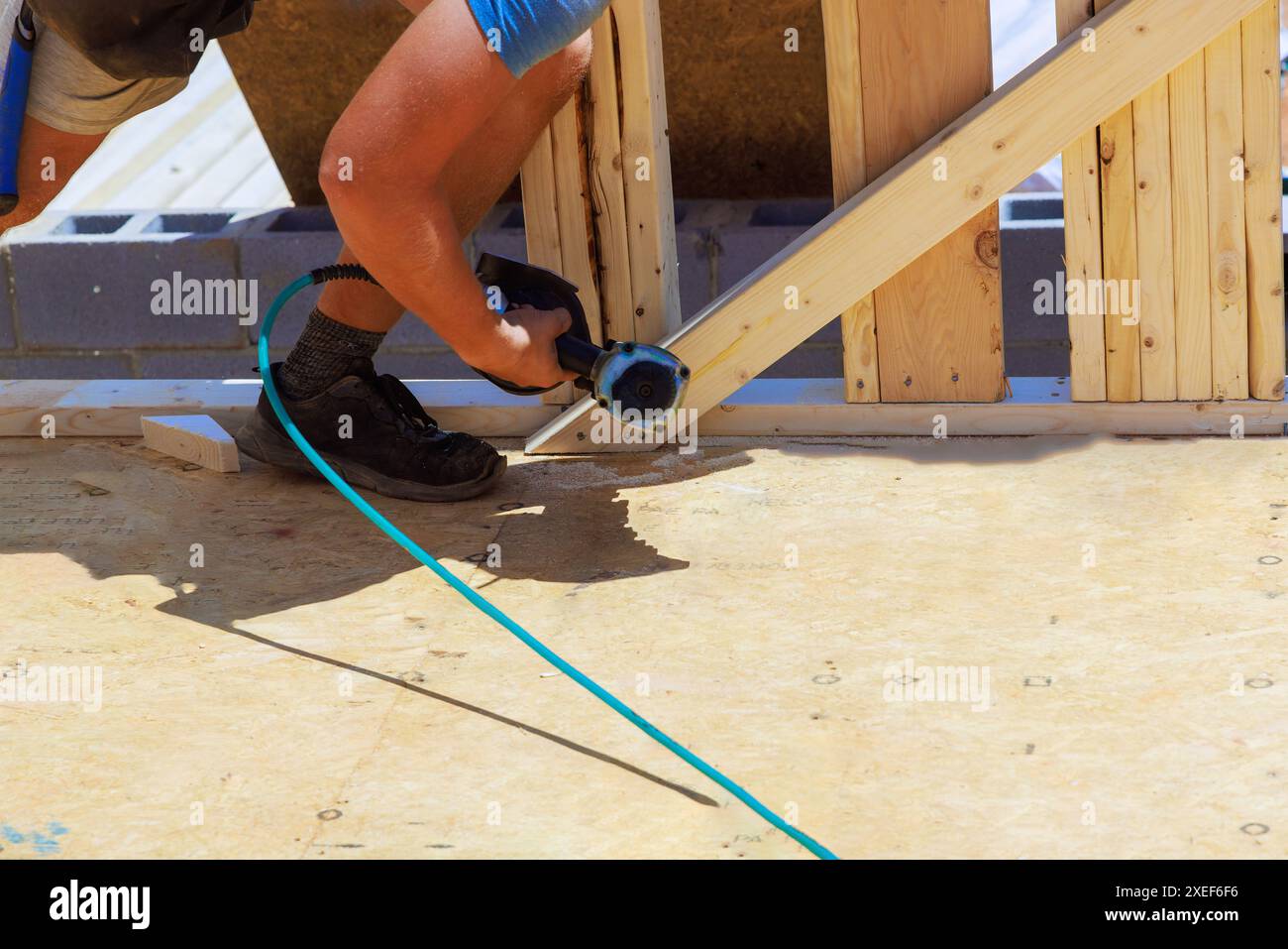 An air nail hammer is used by framing contractor to nail wooden beams ...