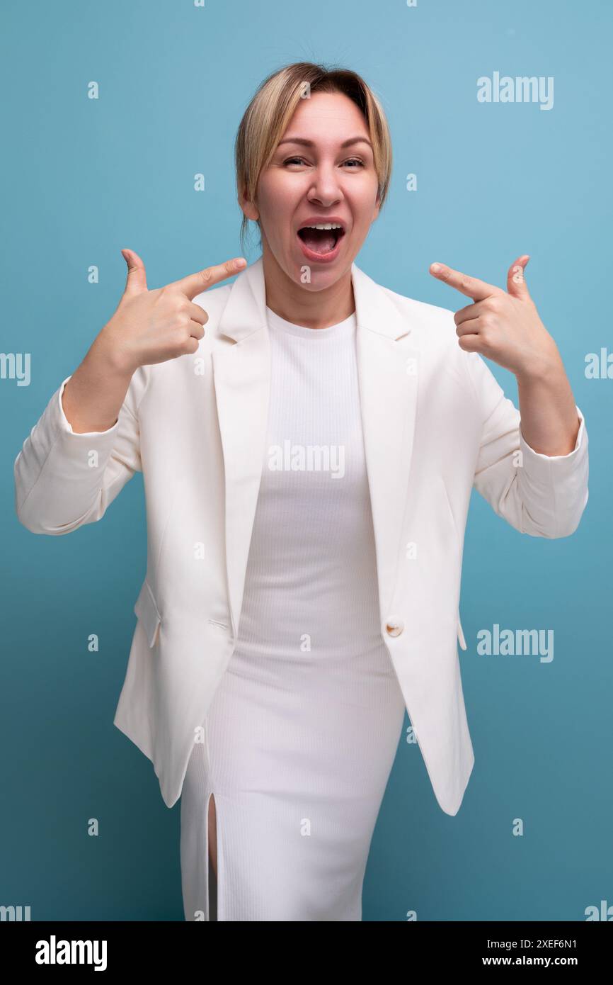 Pretty young fair-haired business woman in a jacket and dress makes a ...