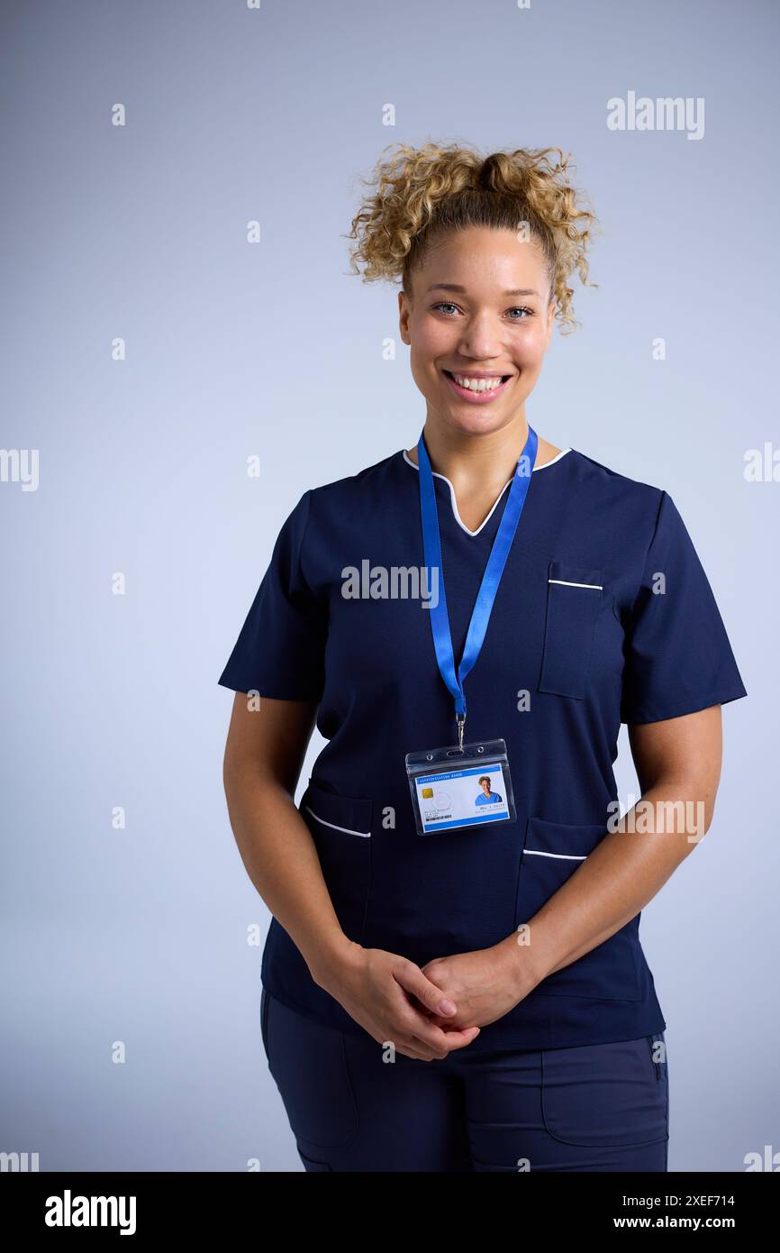 Studio Portrait Of Smiling Female Nurse Wearing Uniform With Security ...