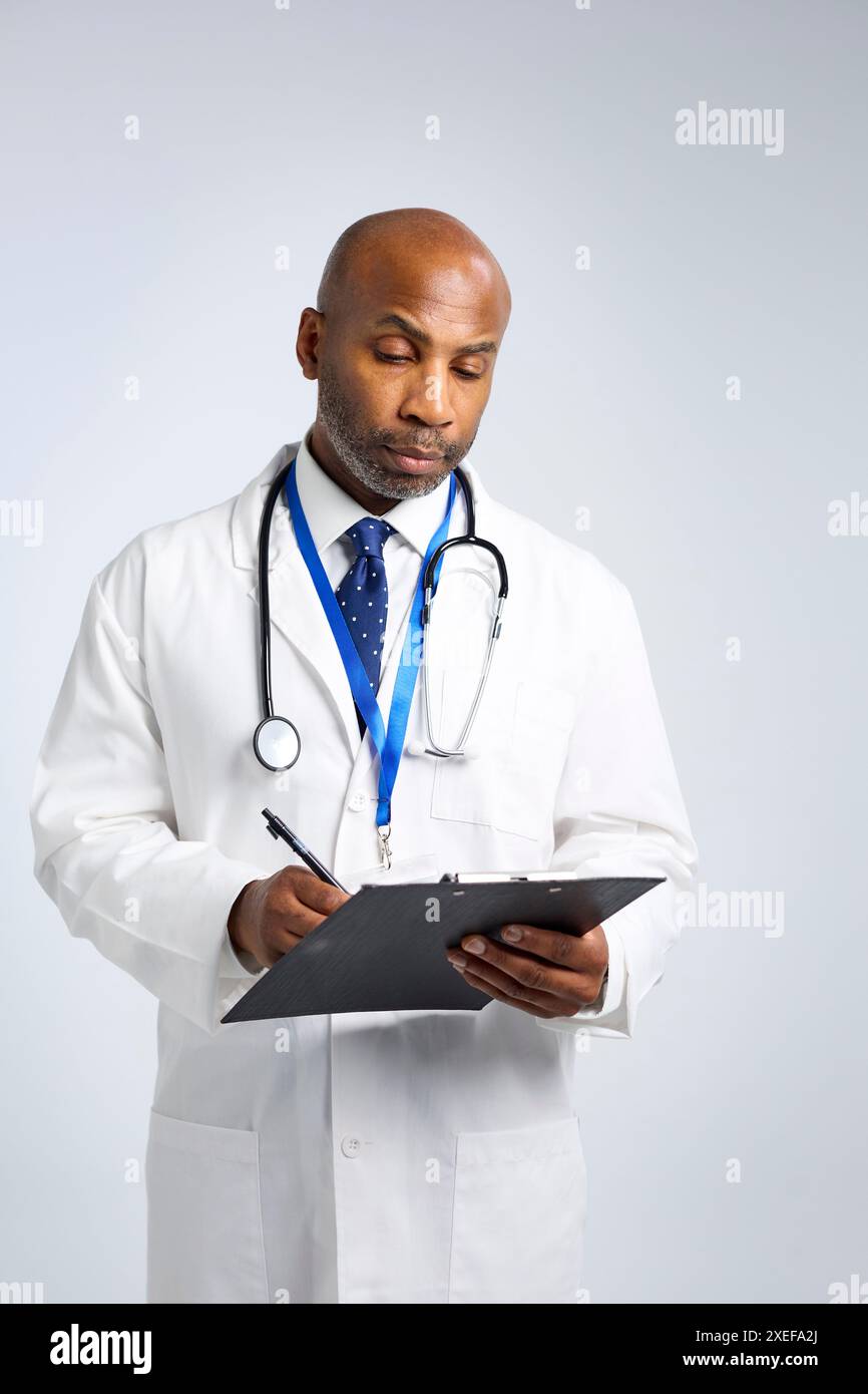 Studio Portrait Of Mature Doctor Wearing White Coat Writing On Patient ...