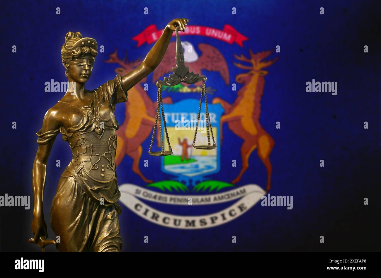 Close-up of a small bronze statuette of Lady Justice before a flag of ...