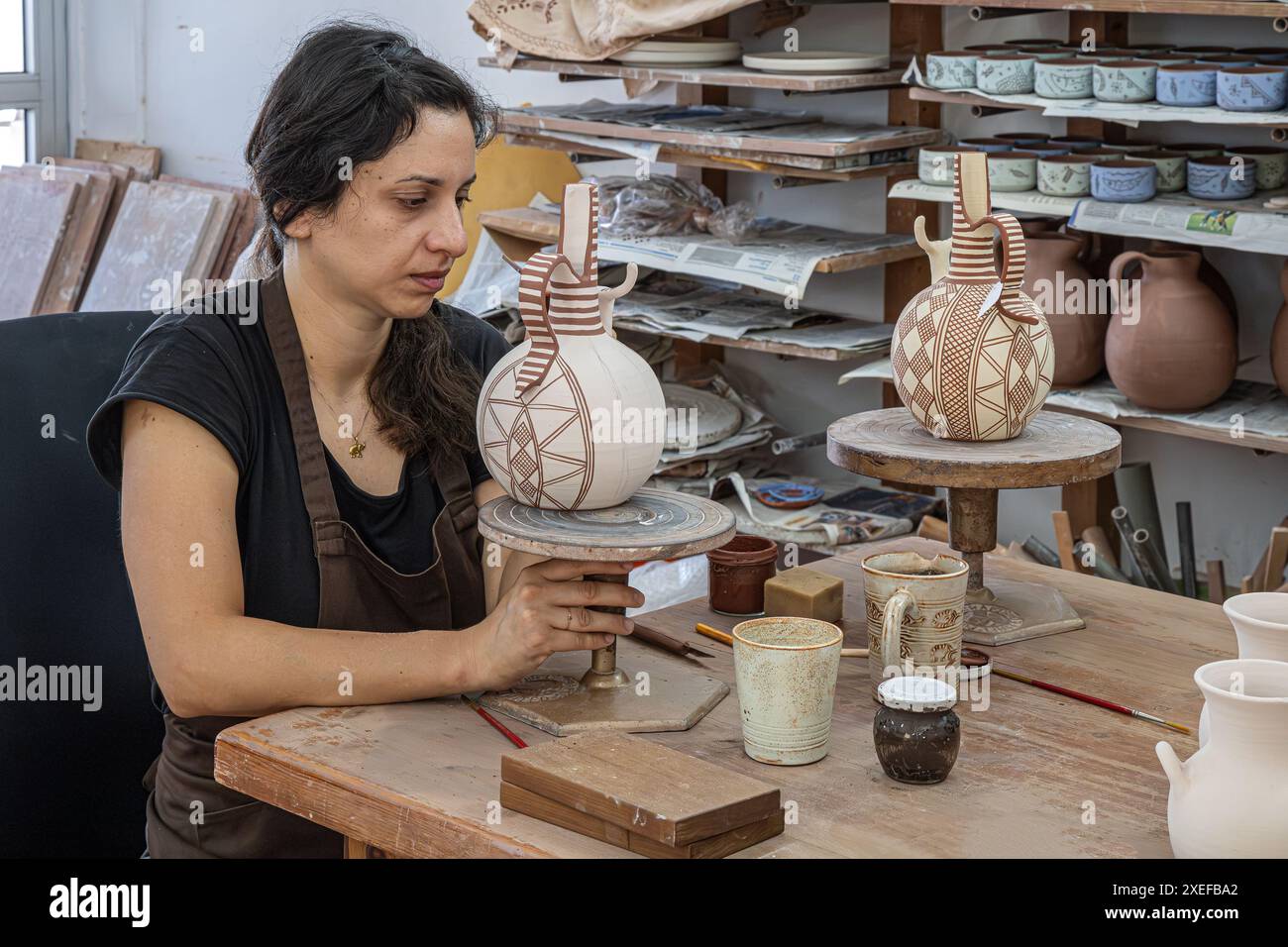NICOSIA, CYPRUS - JUNE 18, 2024: Young woman paints Greek folk art ceramic objects at the Cyprus ...