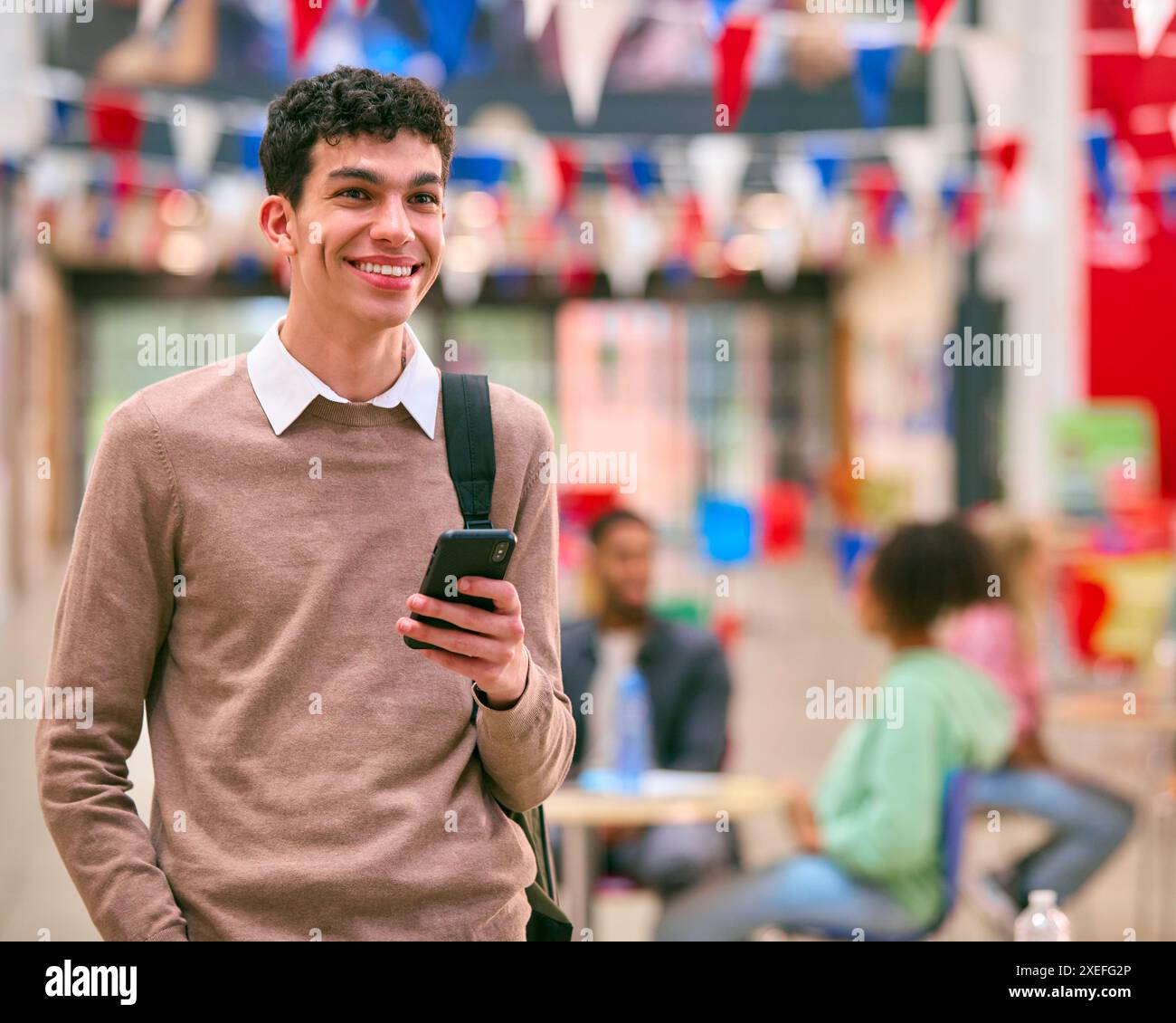 Smiling Male University Student Standing Inside College Building Using ...