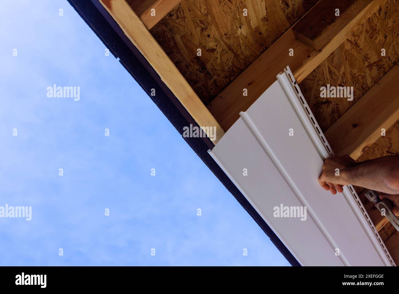 Vinyl soffit plastic panels installed by an employee on facade ceiling ...