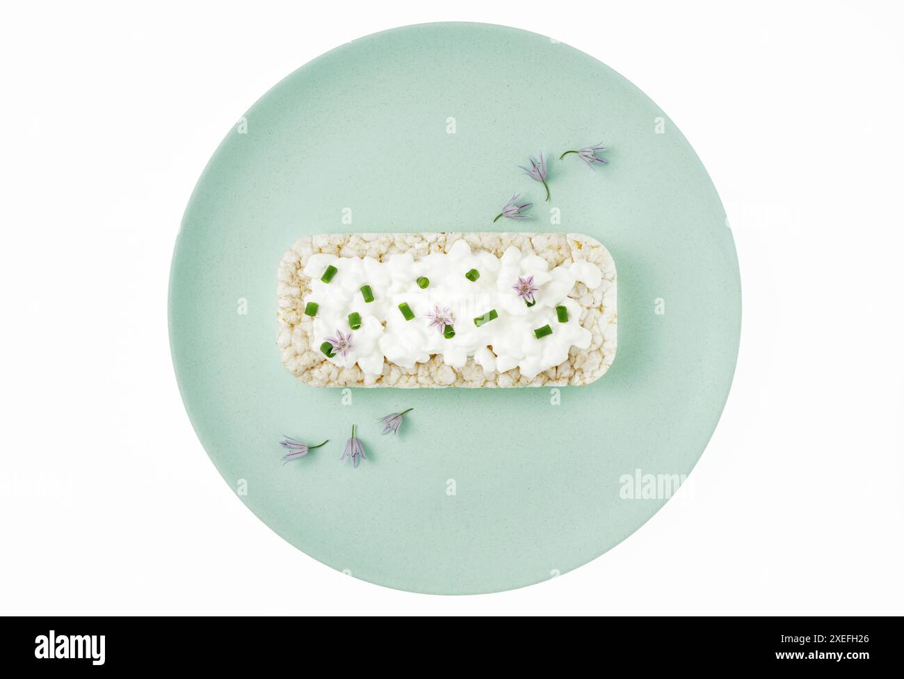 Oblong rice cake on green plate topped with cottage cheese and chives ...
