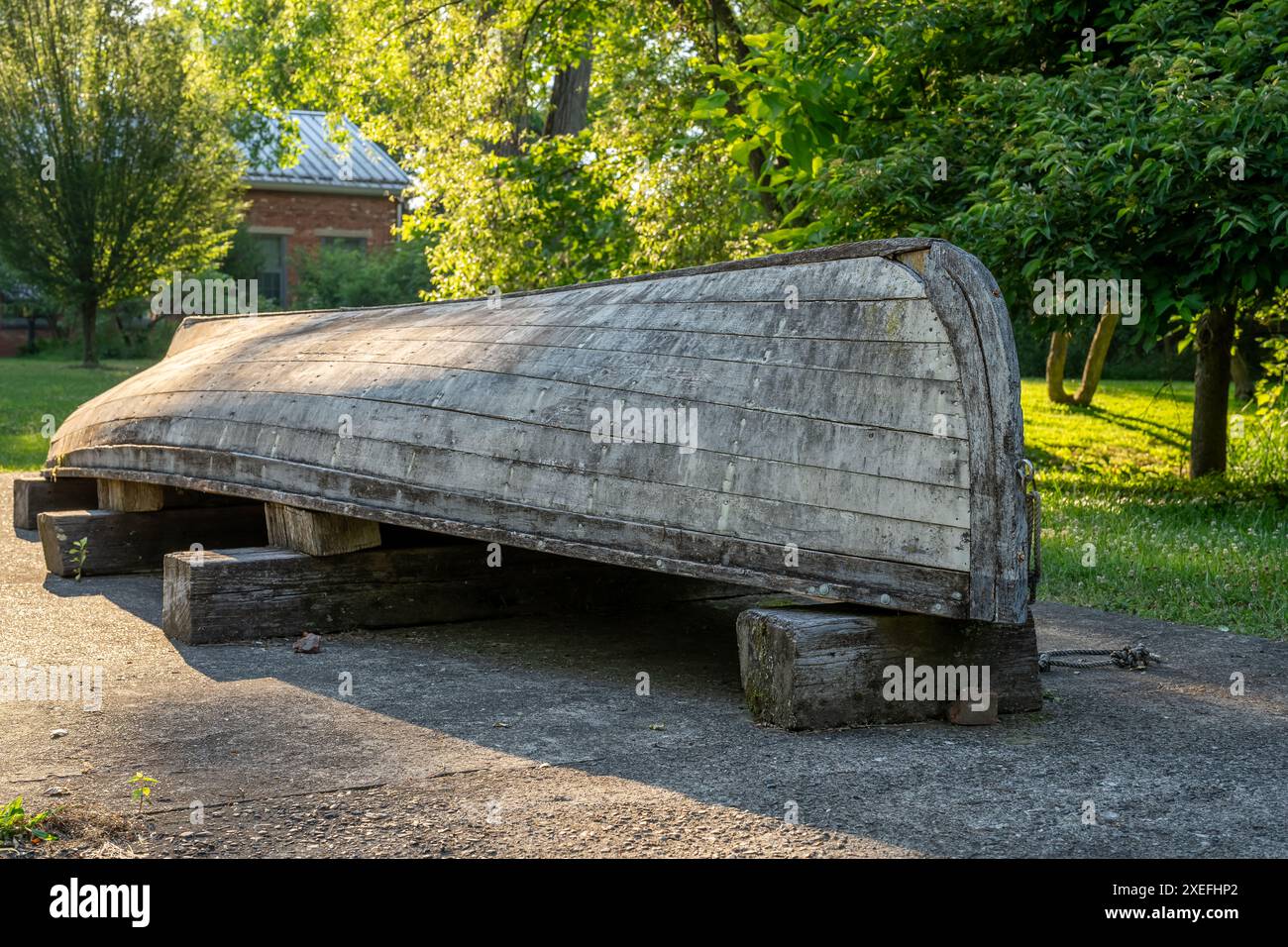Old, weathered, gray wooden row boat upside down, inverted, on blocks ...