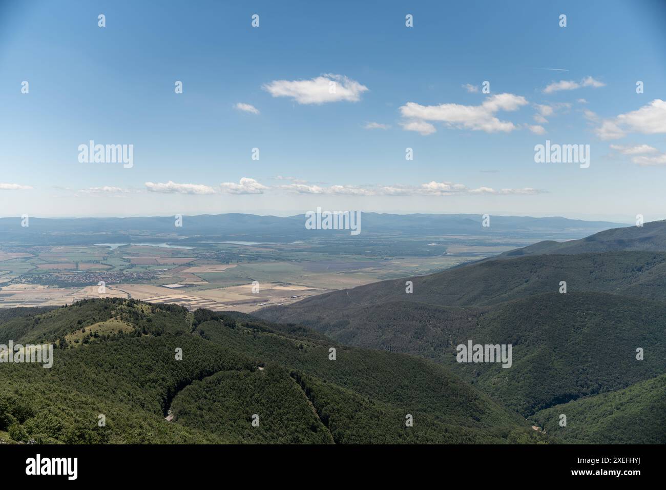 Scenic vista of a vast valley surrounded by rolling hills, bathed in ...
