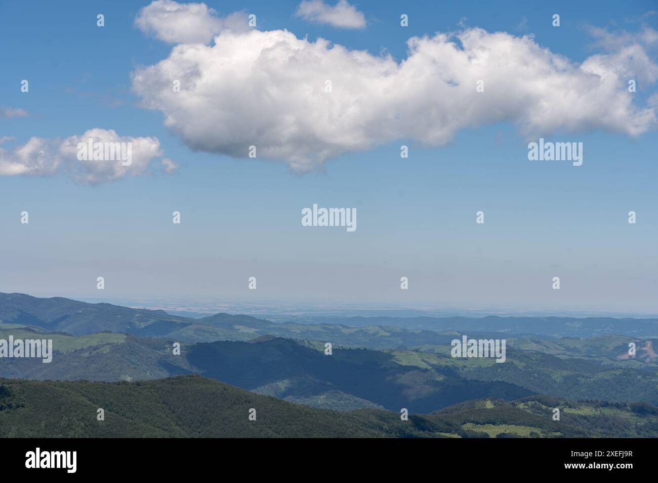 Beautiful landscape of green mountains covered with forest under blue sky with white clouds ...
