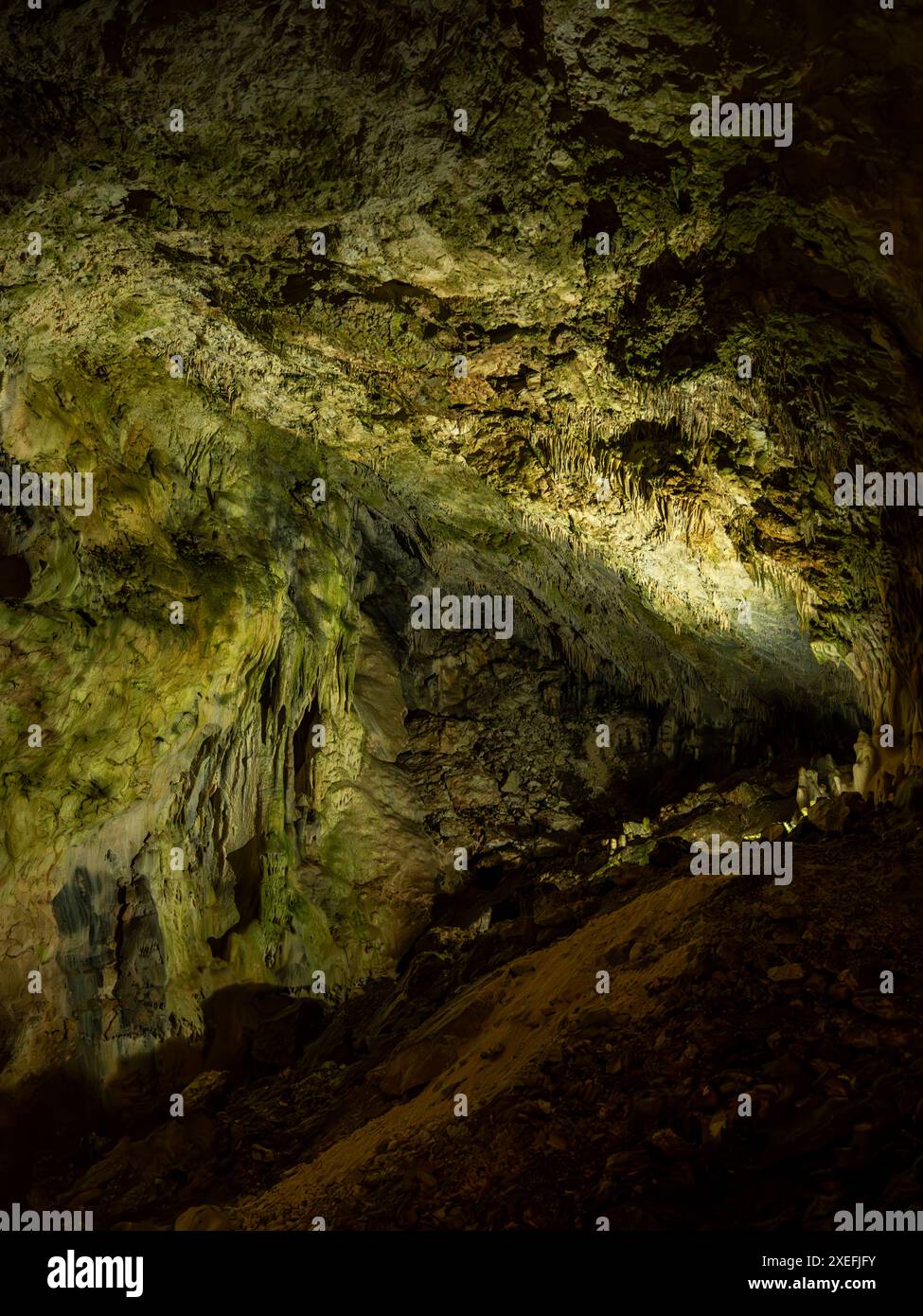 Large cave showing stalactites and stalagmites illuminated by light ...