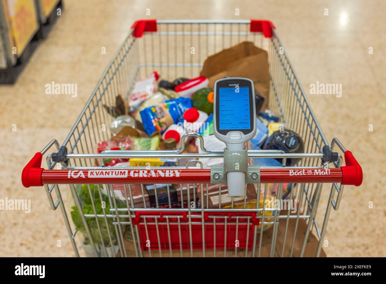 View of shopping cart loaded with groceries and barcode scanner in ...