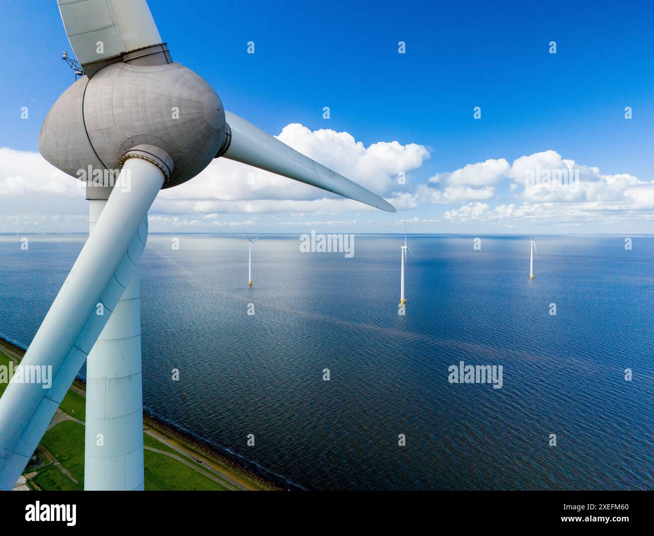 A wind turbine stands tall in the vast ocean, its blades gracefully ...