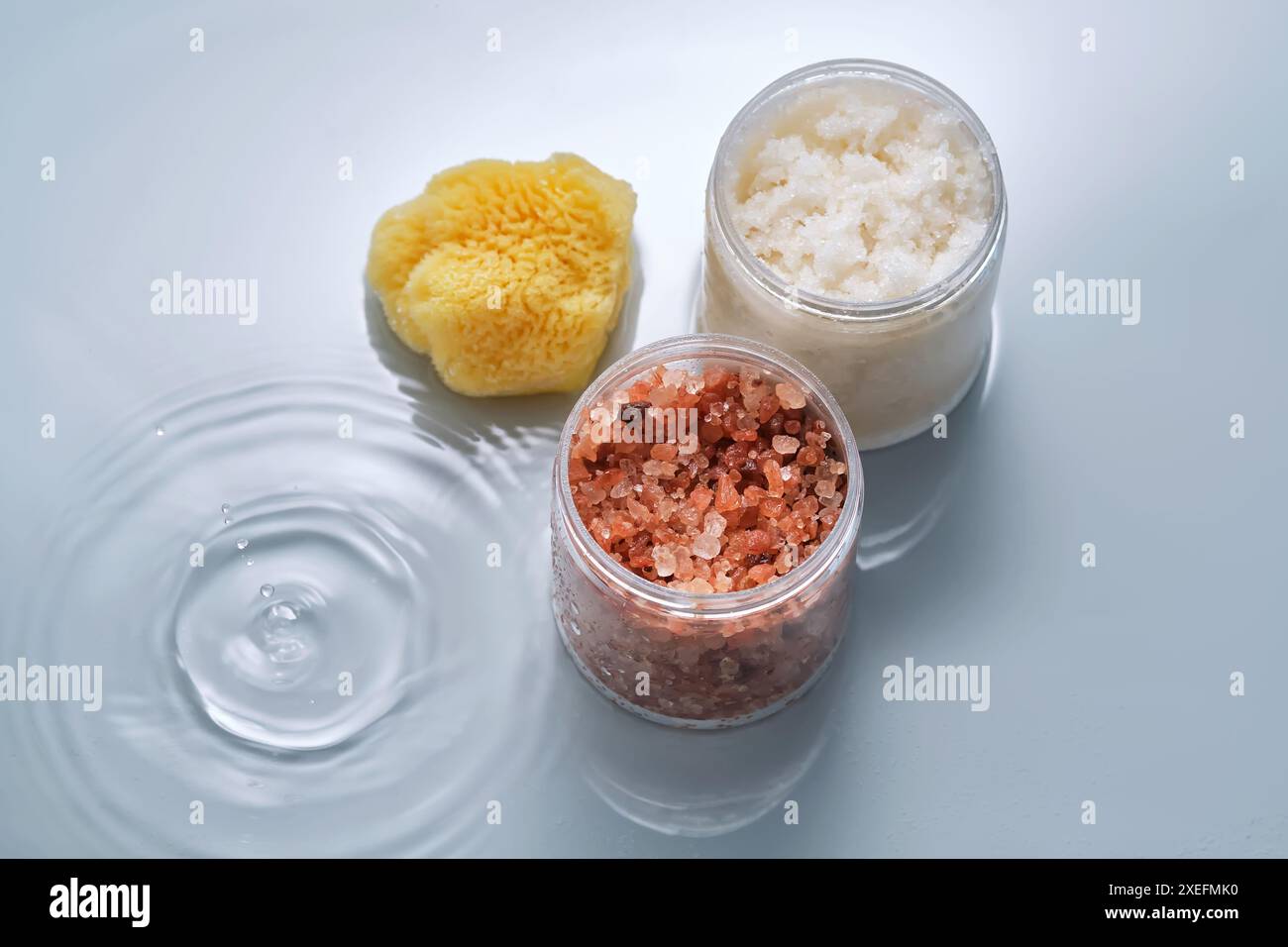 Body scrub, bath salt and natural sponge on a blue background with ...