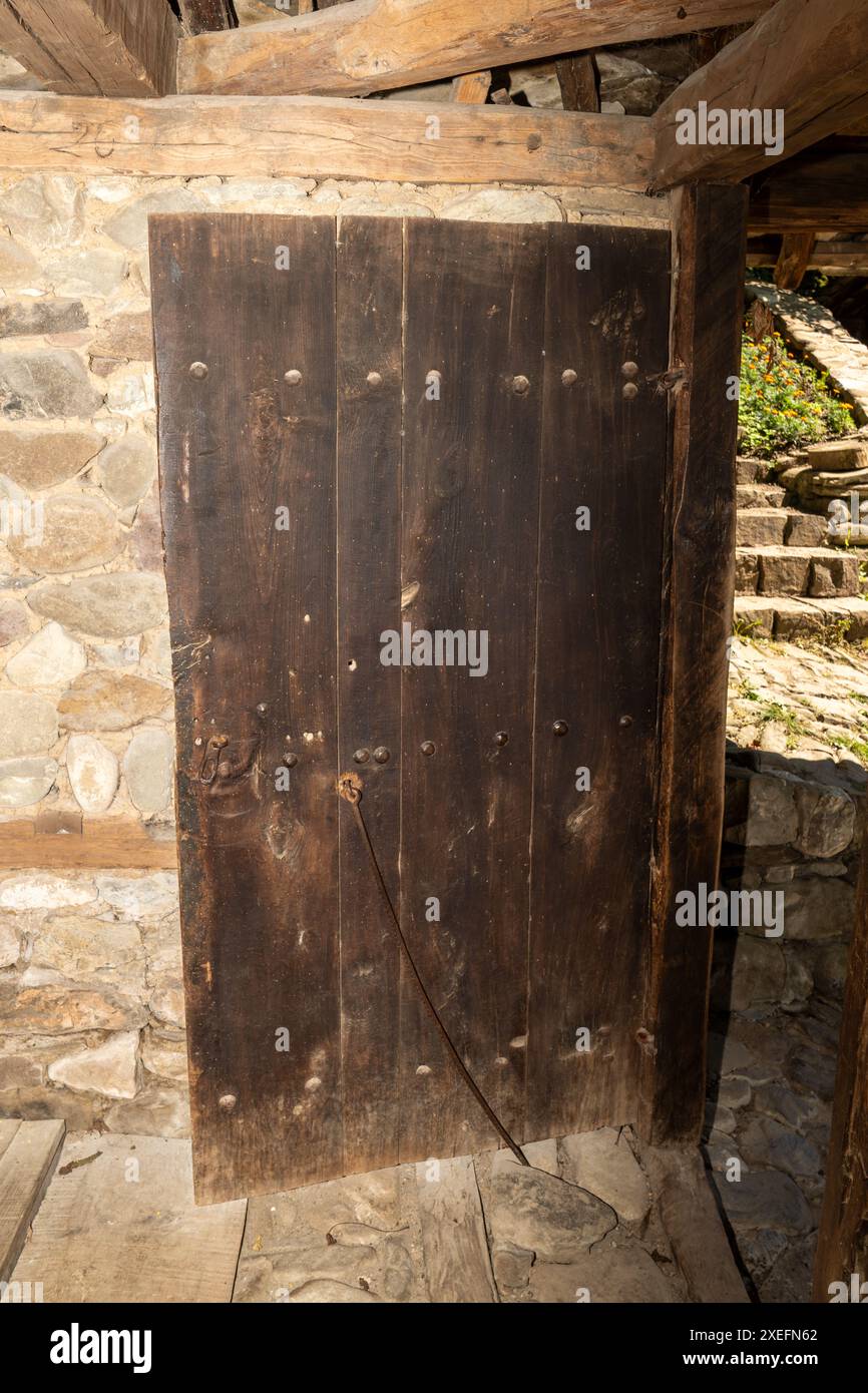 Old wooden door with metal hardware is standing open in a stone wall ...