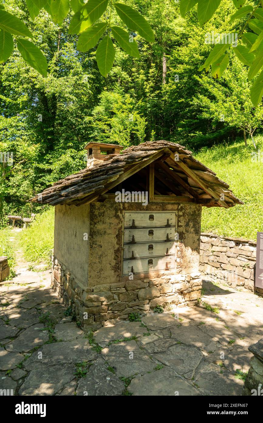 Rustic smokehouse with stone foundation and shingle roof standing in a ...