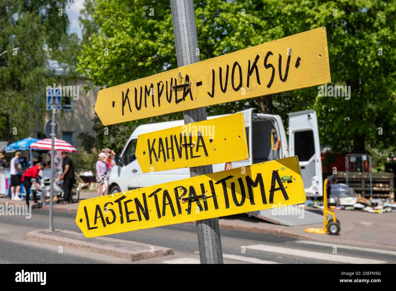Yellow wooden direction signs on tilted traffic sign at Kumpula Village ...