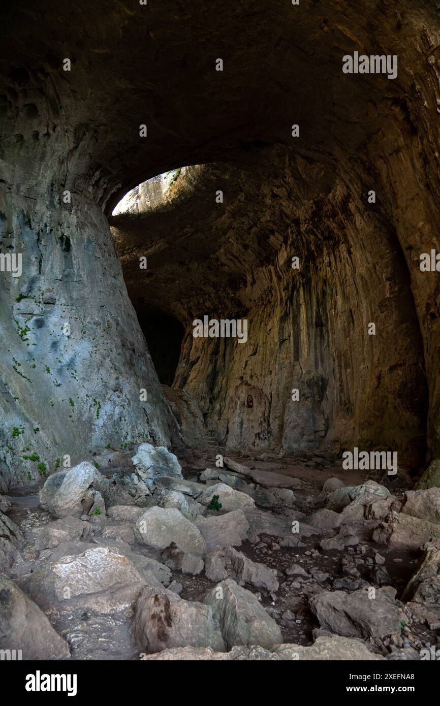 Light is illuminating rocks on the ground of a big natural bridge in a ...