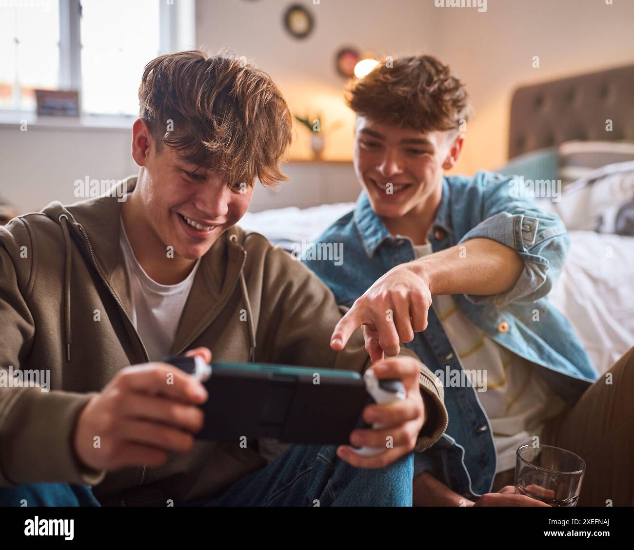 Two Teenage Boys At Home In Bedroom Together Playing On Handheld ...