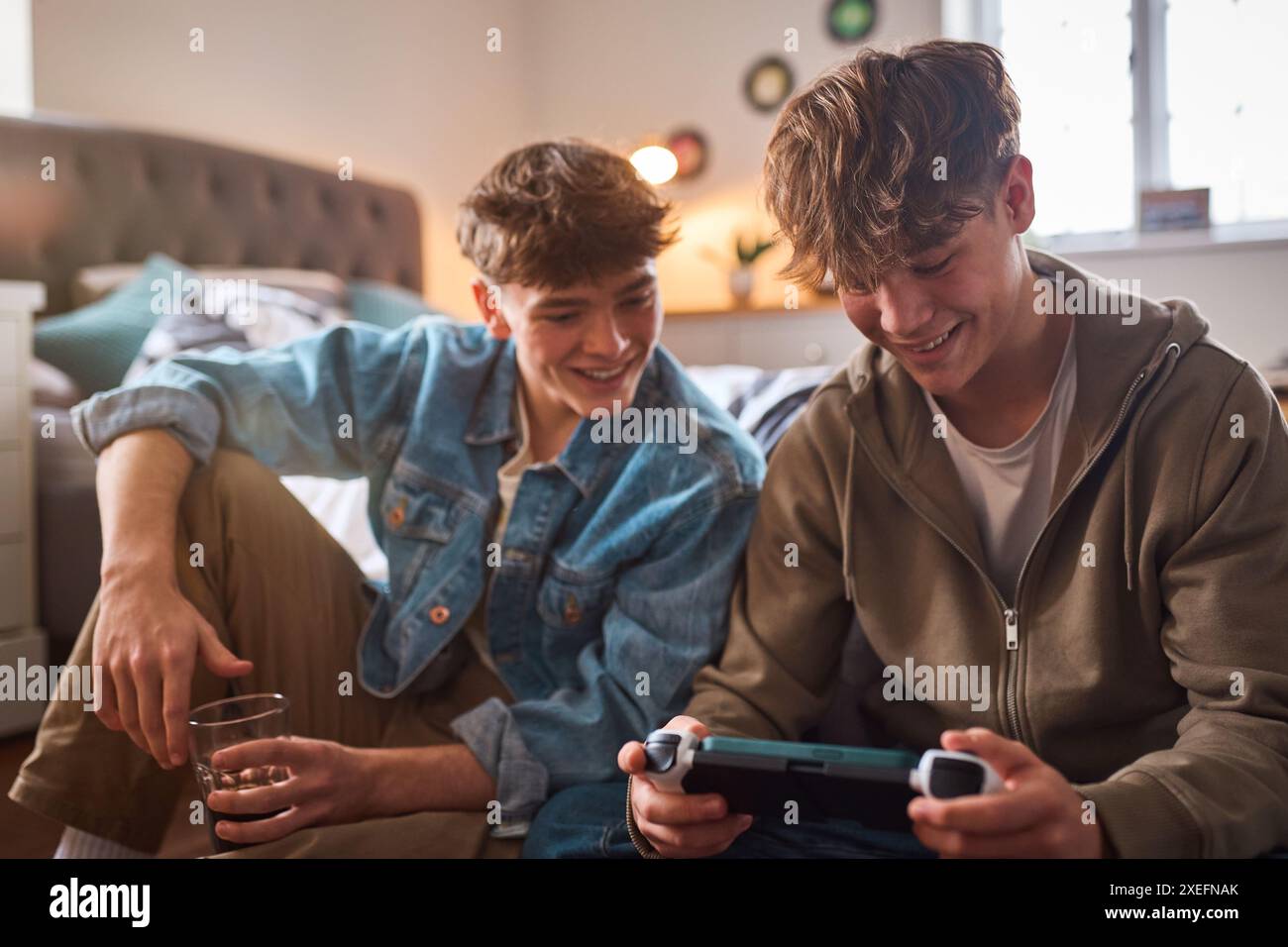 Two Teenage Boys At Home In Bedroom Together Playing On Handheld ...