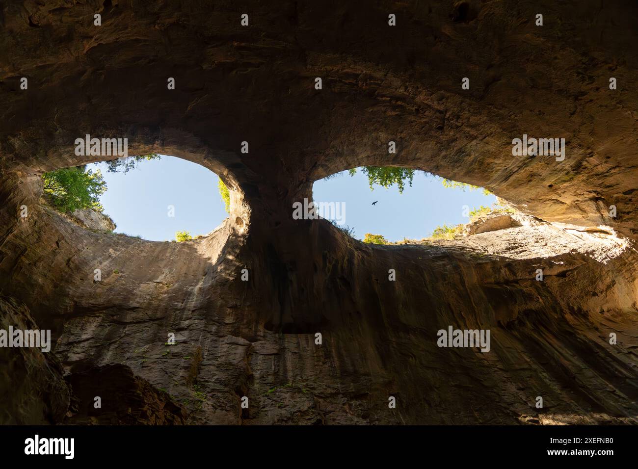 Sunlight entering through two openings in the ceiling of a large cave ...