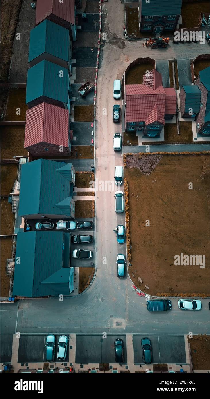 Aerial view of a suburban neighborhood with houses, parked cars, and a ...