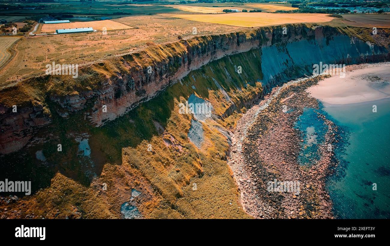 Aerial view of a coastal cliff with a rocky shoreline and a sandy beach ...