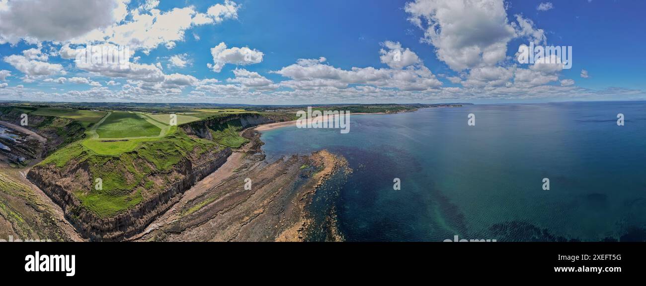 Aerial view of a coastal landscape with green cliffs, rocky shoreline ...