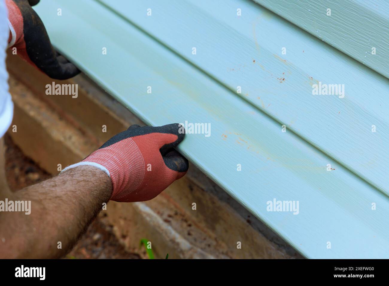 During construction, worker installs vinyl plastic siding on wall ...