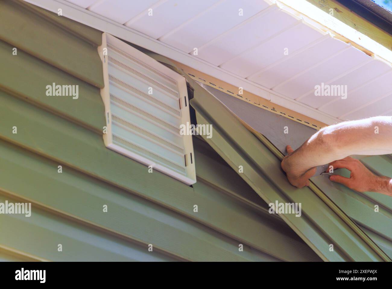 During construction, an employee installs vinyl plastic siding panels ...