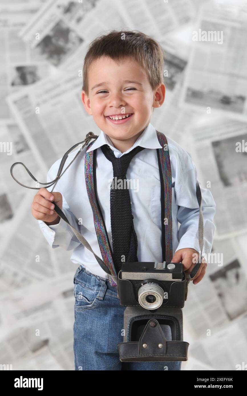 cute little boy with vintage photographic camera with newspapers in ...