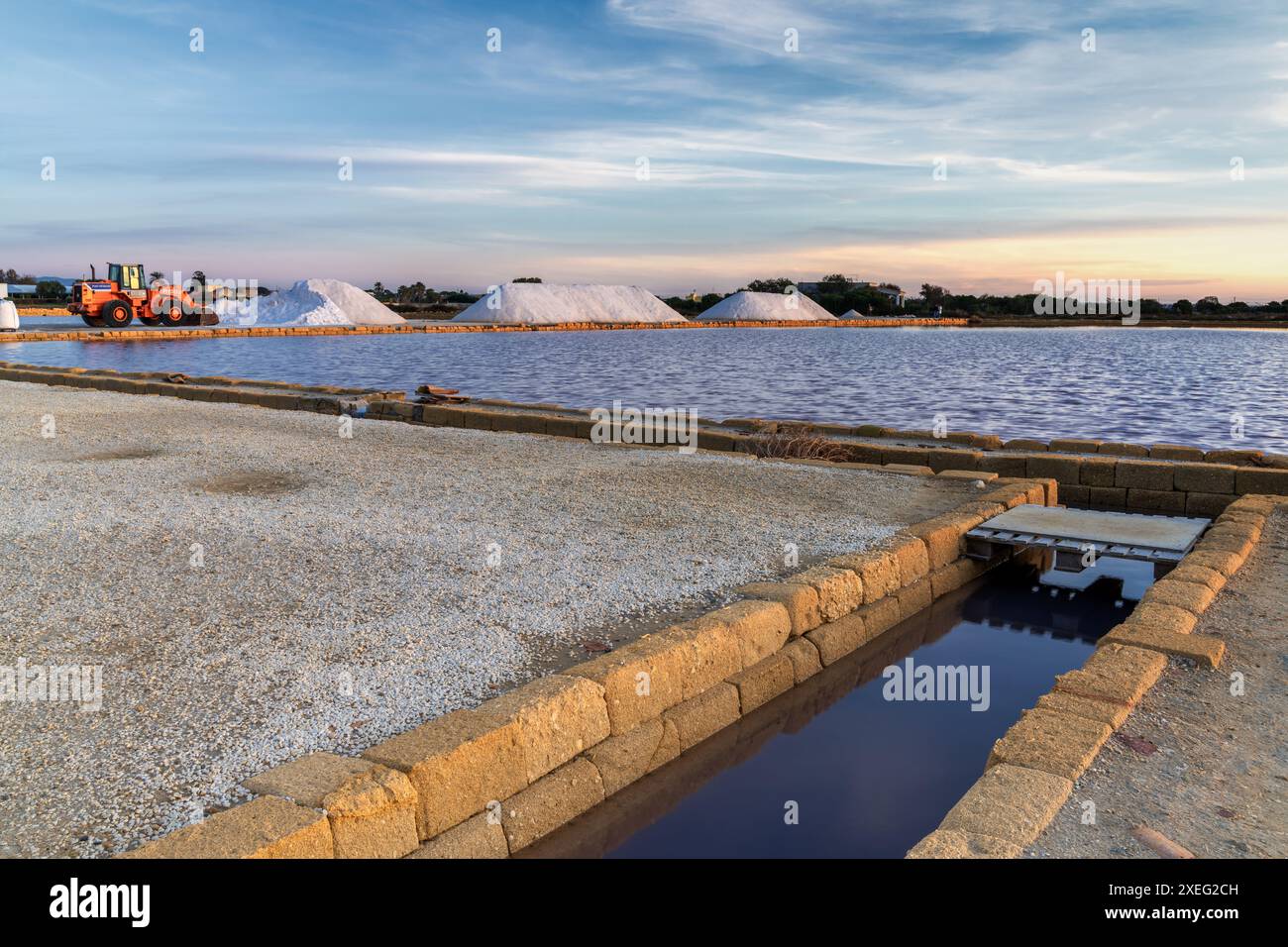 Front loader and piles of sea salt in the salt flat of Trapani and ...