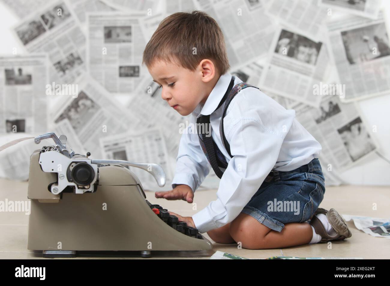 cute little boy playing with vintage typewriter with newspapers in ...