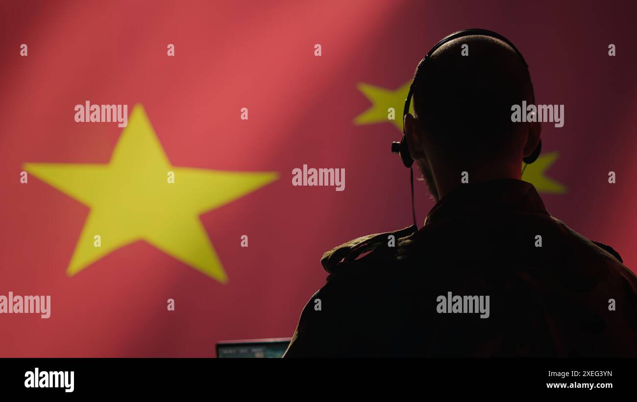 Chinese army military dispatcher looking at surveillance transmission on laptop, relaying ...