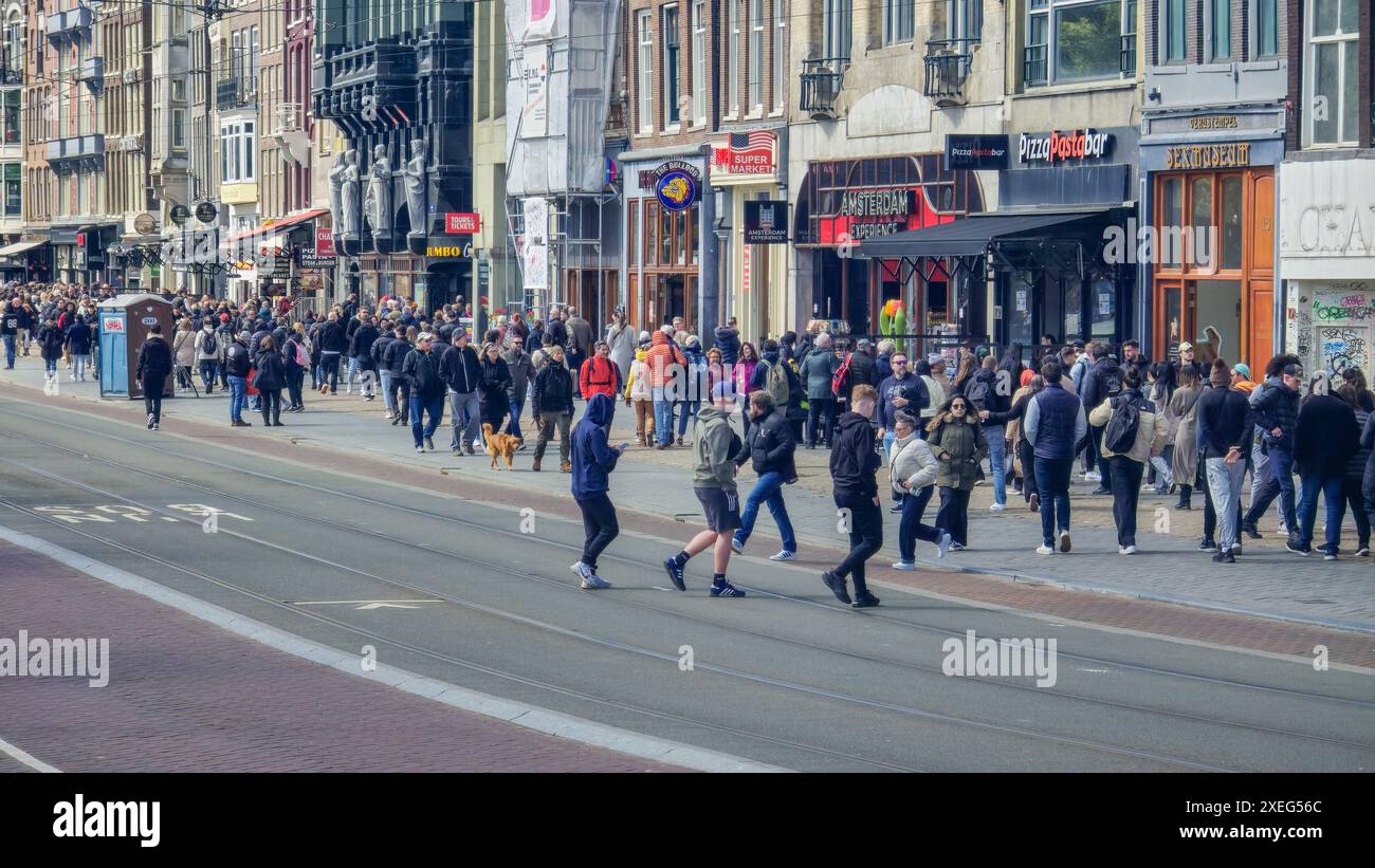 A diverse crowd of people walks briskly down a bustling city street ...