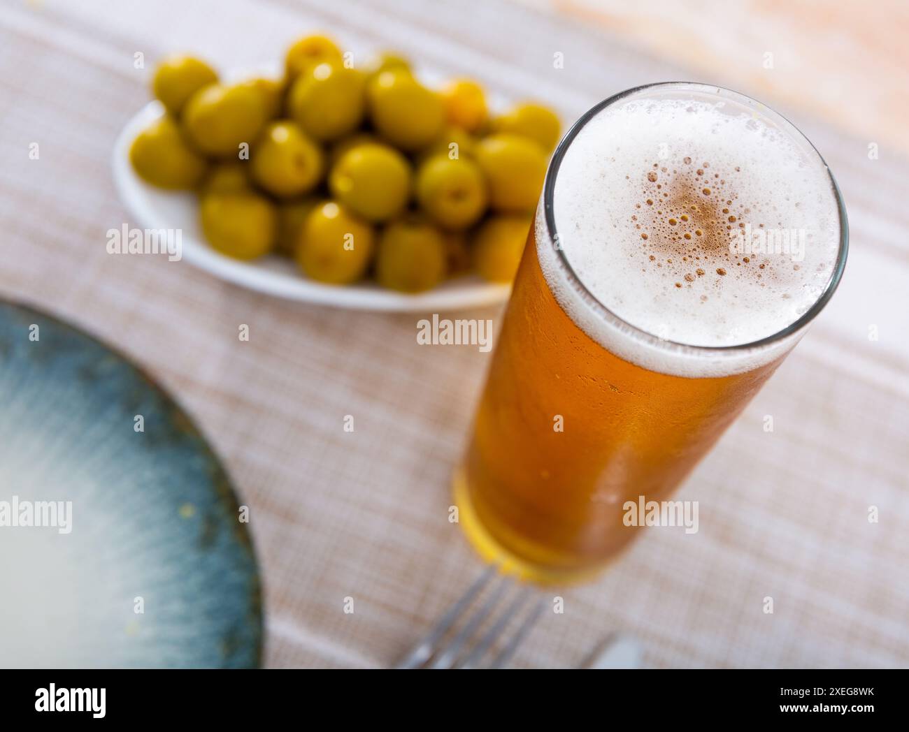 Glass of lager beer with foamy head served with olives Stock Photo - Alamy