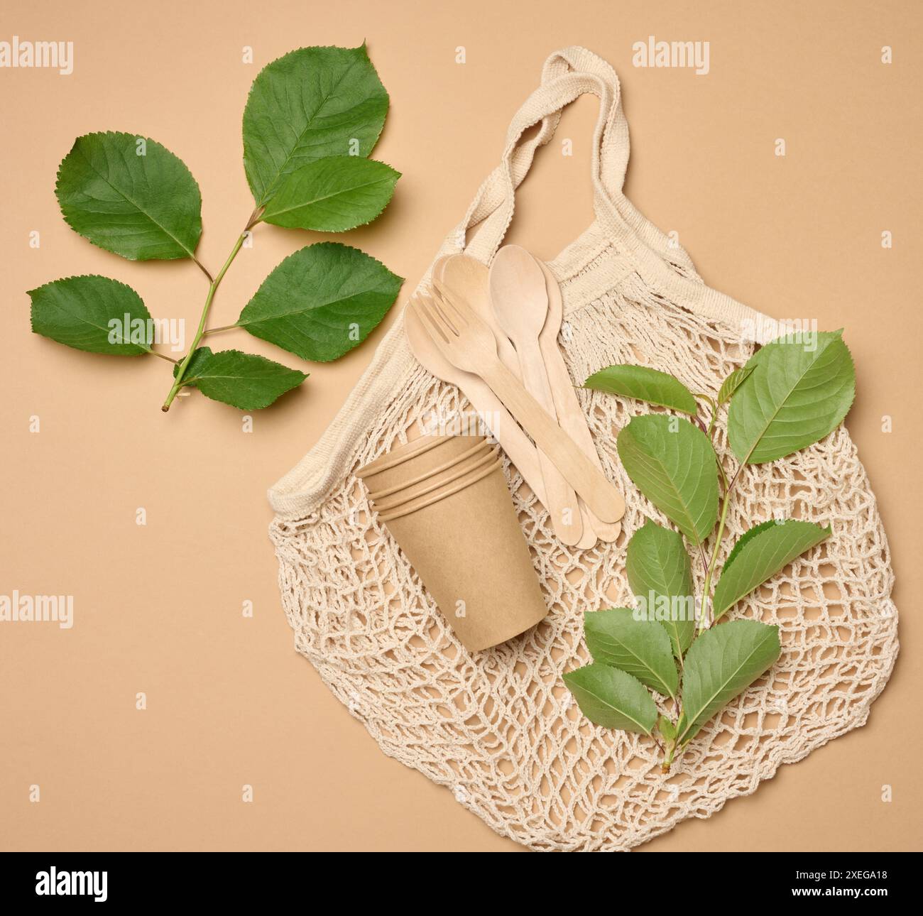 Textile knitted string bag and a stack of disposable cardboard glasses ...