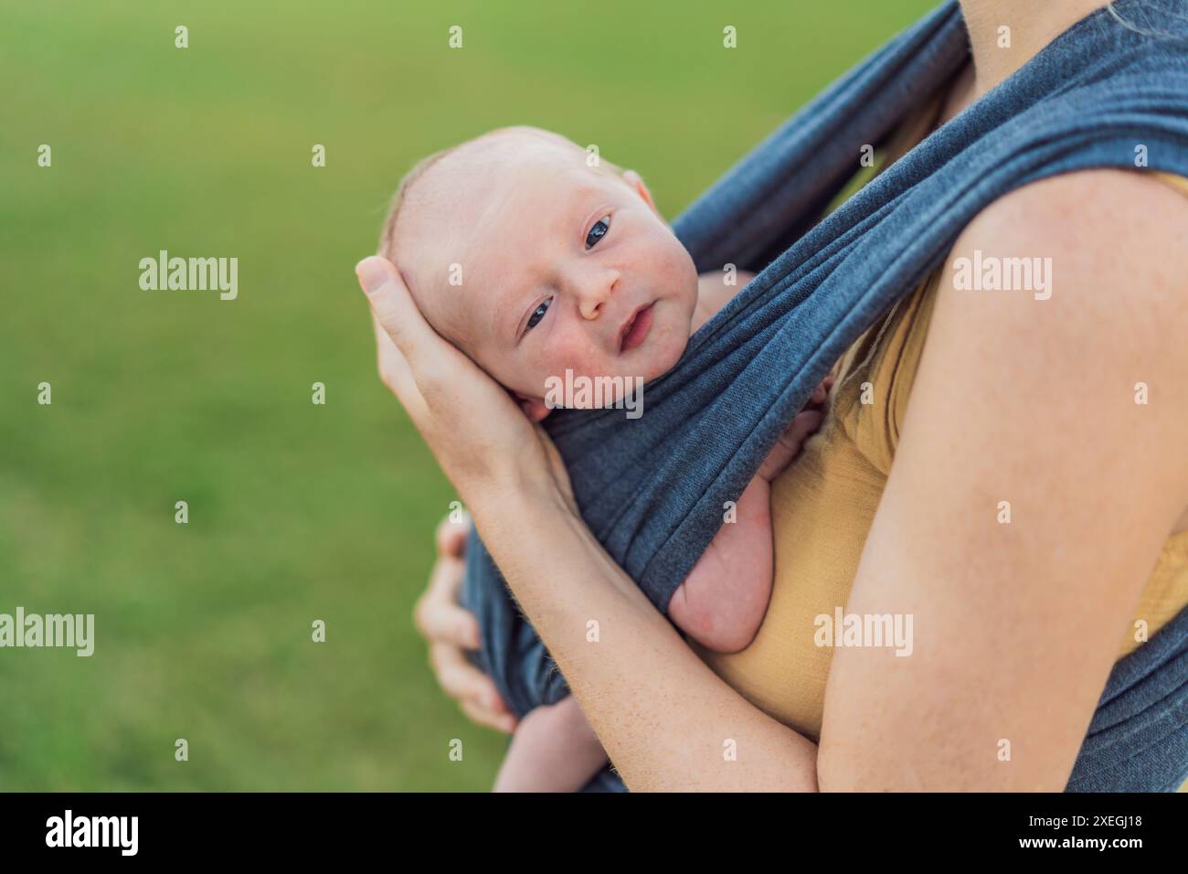 Mom walks with her newborn baby in a sling. This moment highlights the ...
