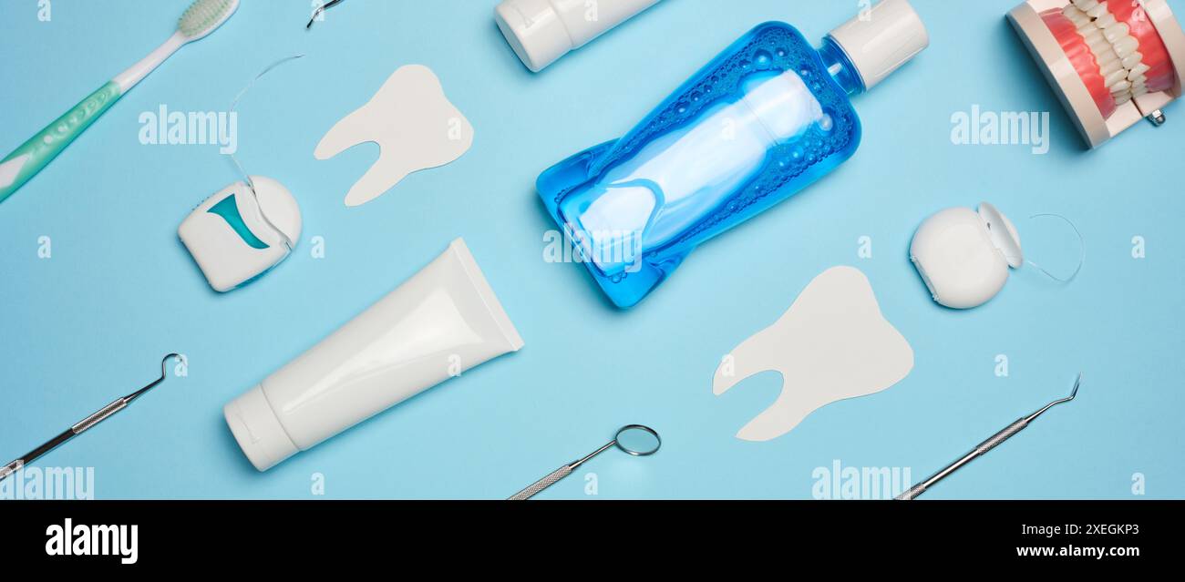 Mouthwash, toothpaste tube, dental floss and medical mirror on a blue ...