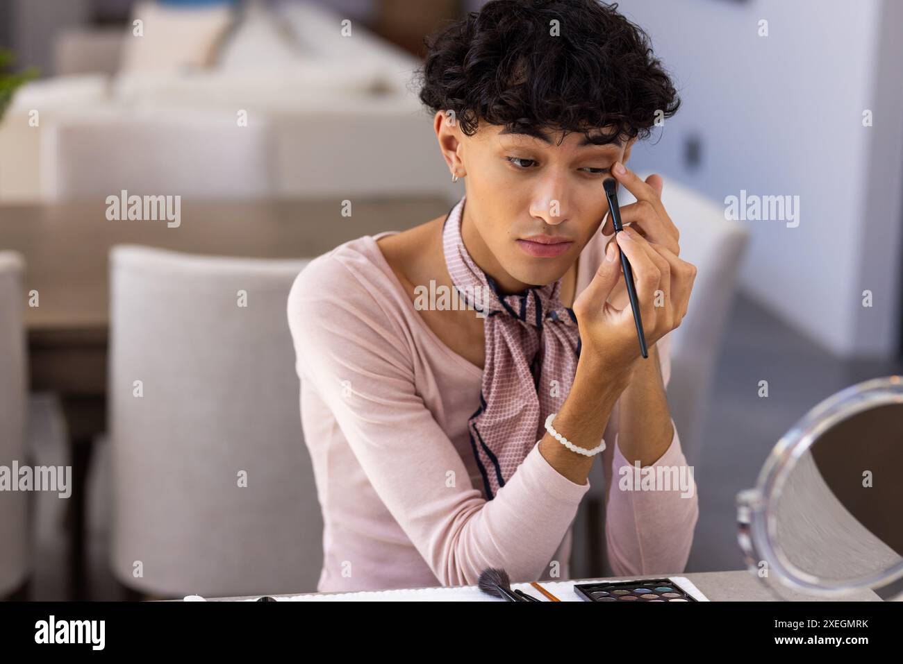 Applying eyeliner, transgender transgender woman using makeup brush in ...