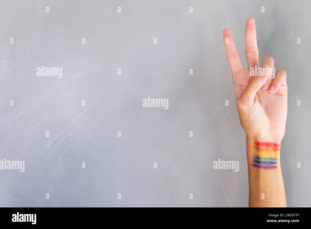 Hand showing peace sign with rainbow flag painted on wrist, expressing ...