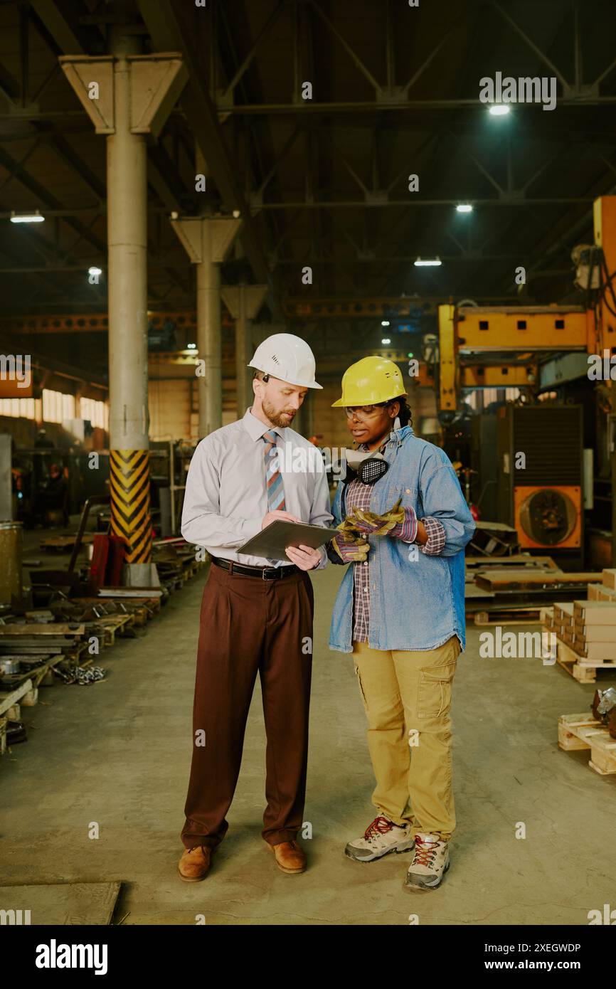 Vertical shot of biracial male engineer and female technician working ...