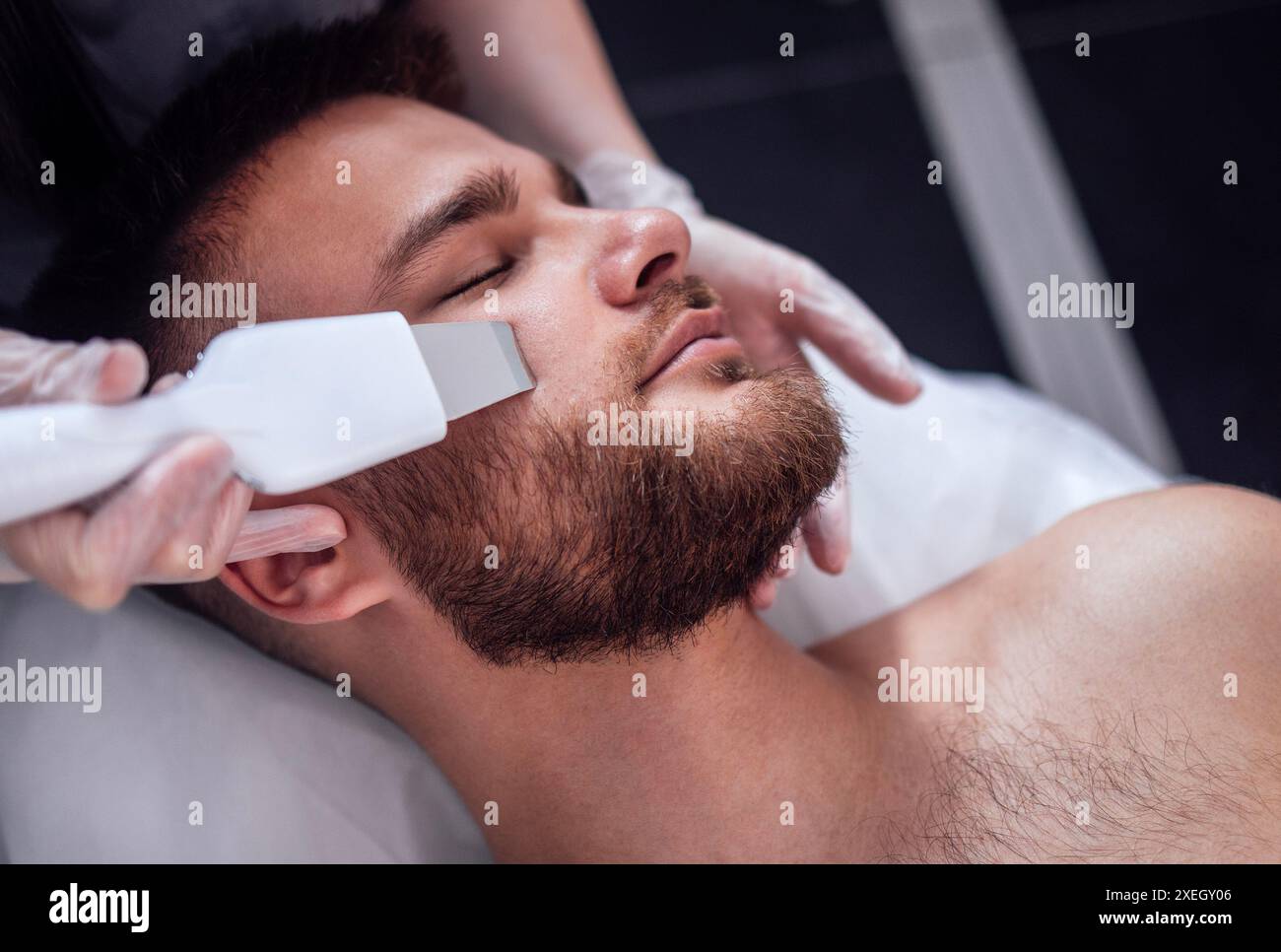 Beauty master makes ultrasonic facial peeling to her client. Young ...