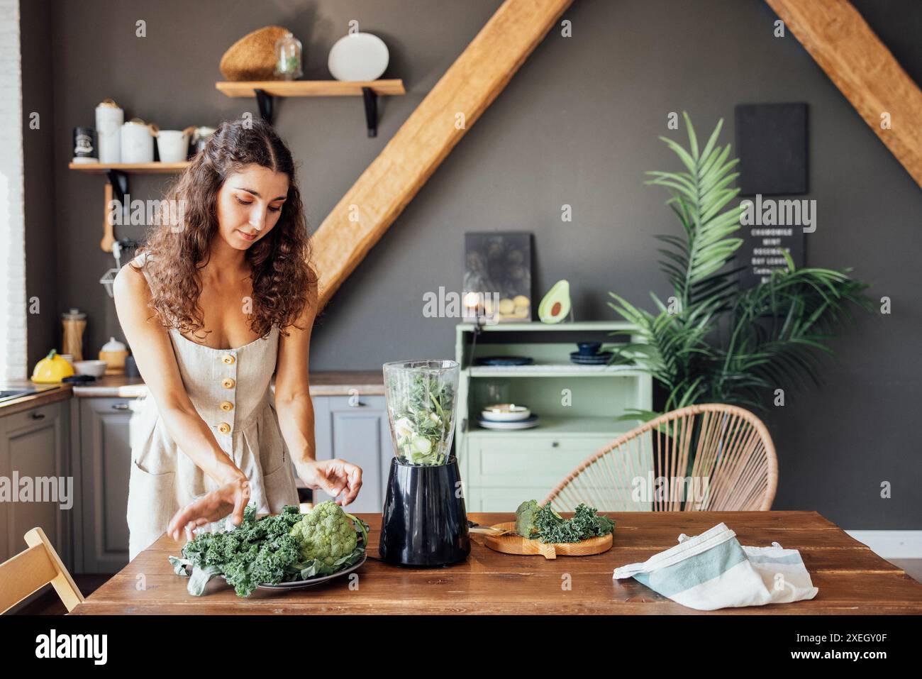 A charming curly-haired brunette girl in a linen sundress prepares a ...